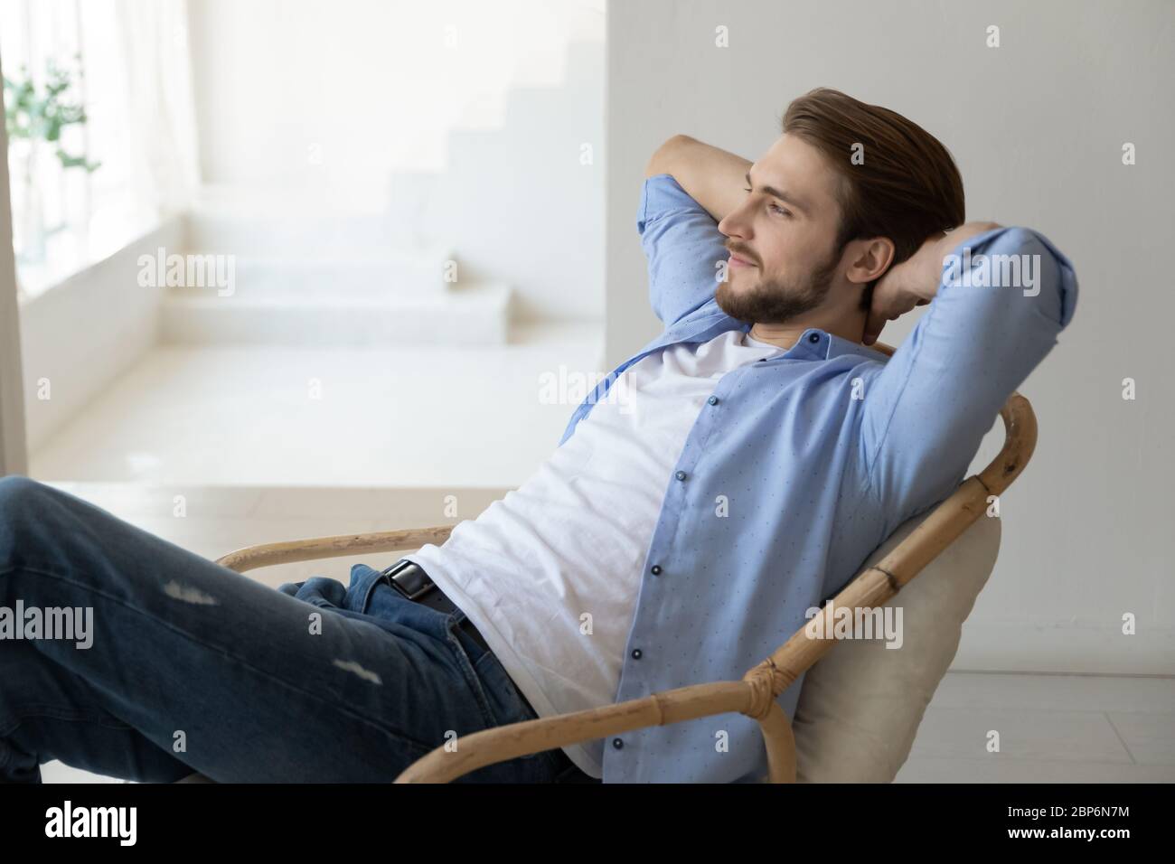 Smiling young man relax in chair visualizing Stock Photo - Alamy