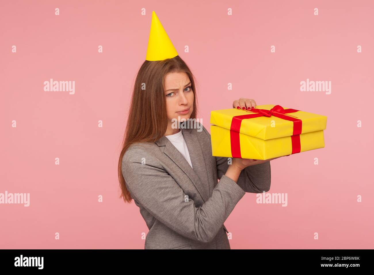 Portrait of upset displeased woman in business suit and with party cone ...