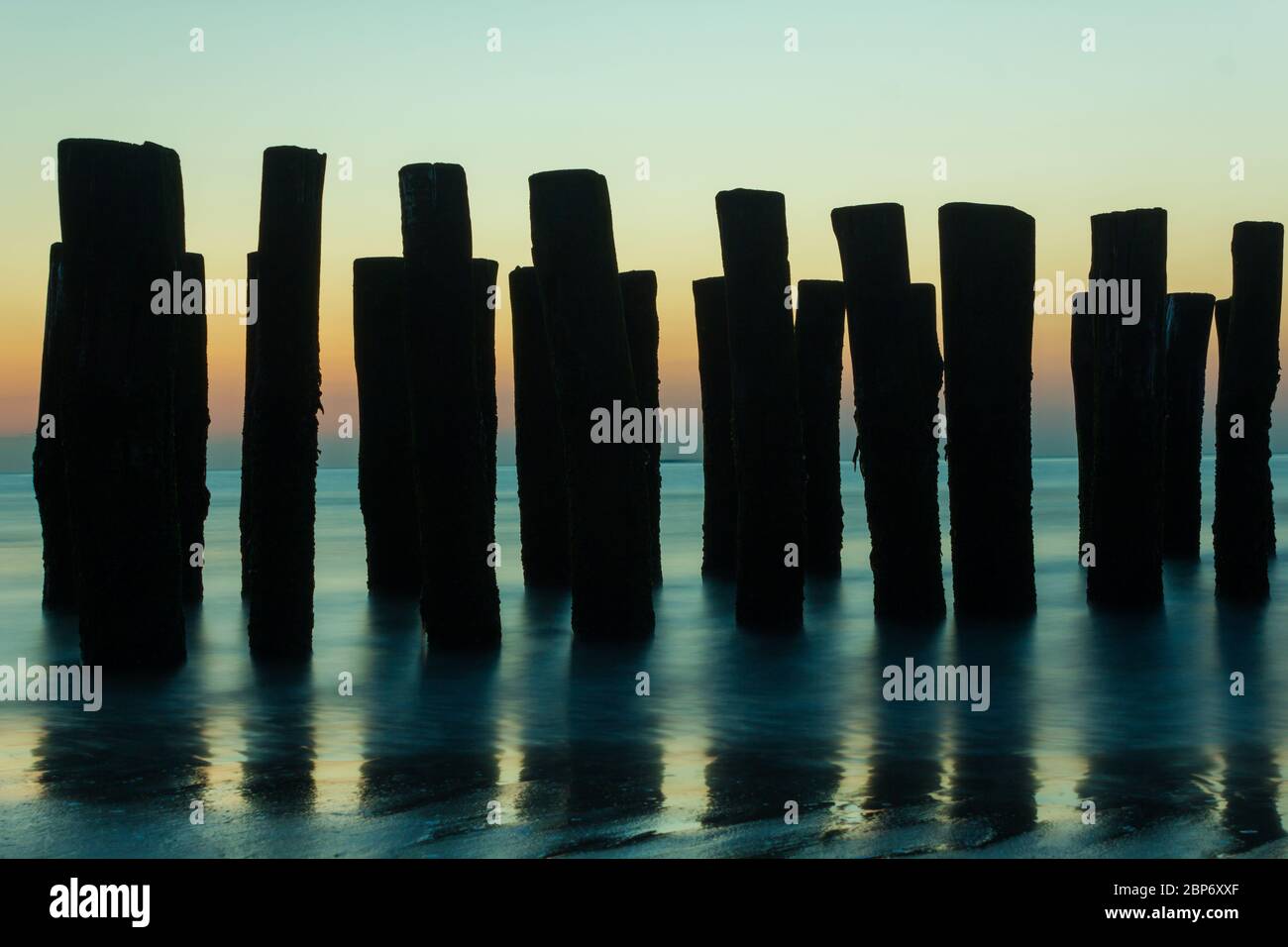 Beautiful silhouette of wooden poles (breakwater) with rising tide in ...