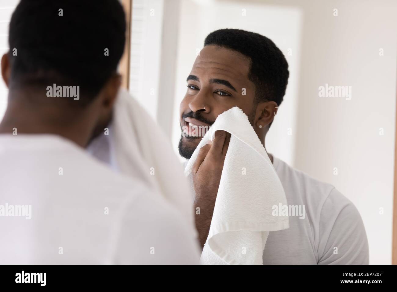 Young biracial man wash wipe face in home bathroom Stock Photo - Alamy
