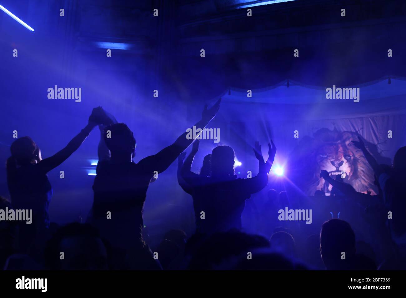 People Raising hands against blue smoky background with light beams ...