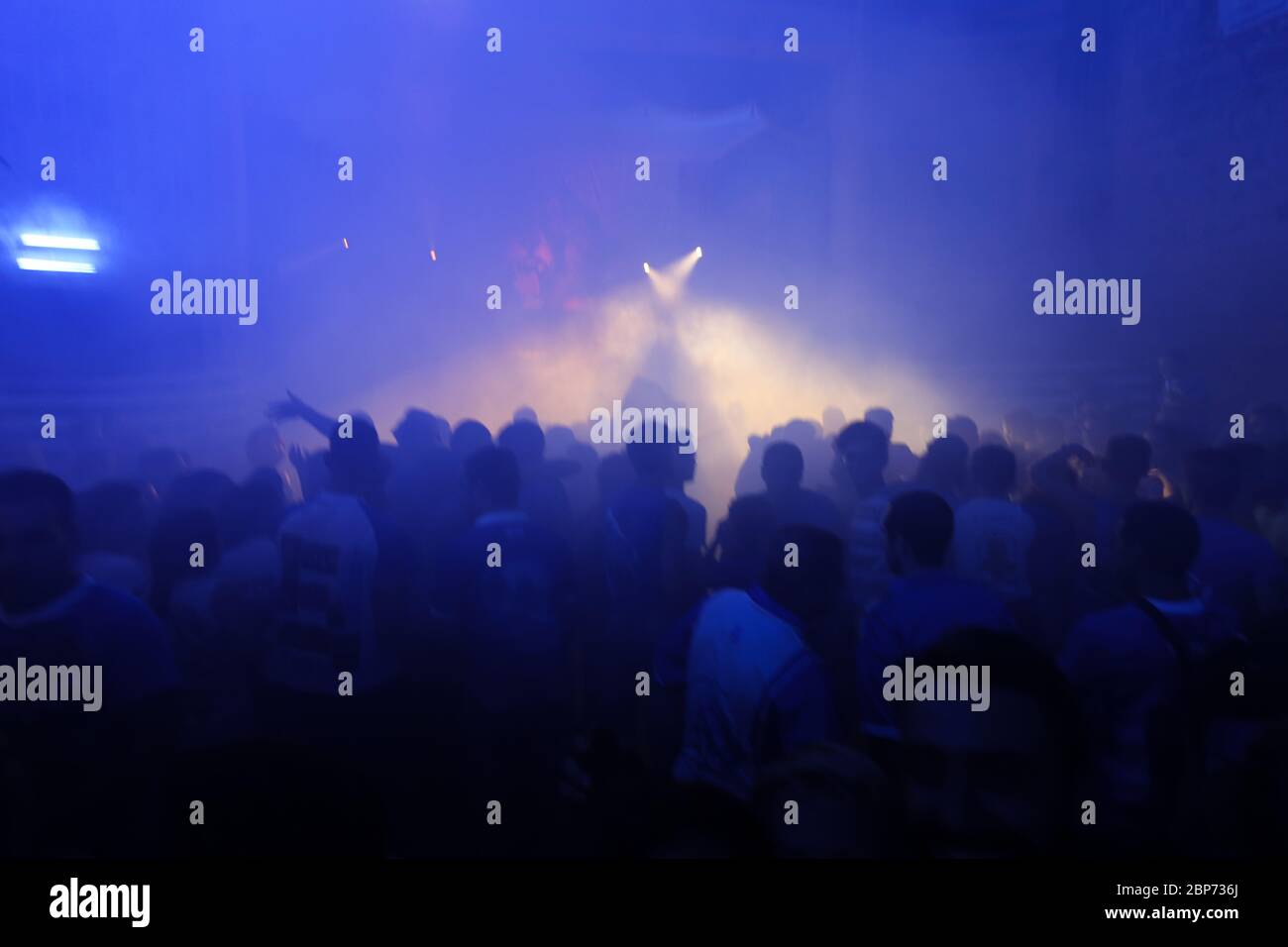 People Raising hands against blue smoky background with light beams ...