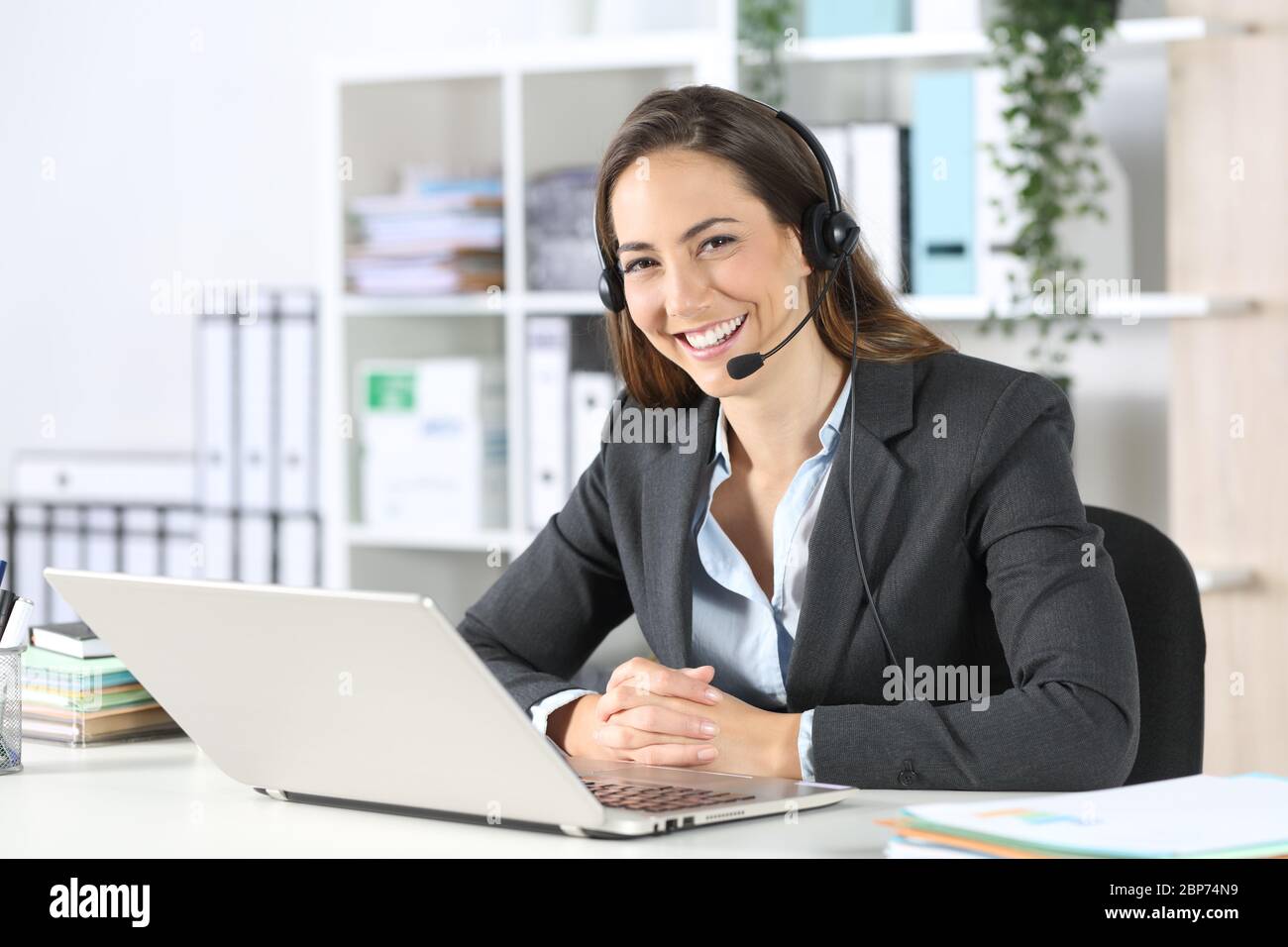 Happy telemarketer woman with headset and laptop posing looking at ...