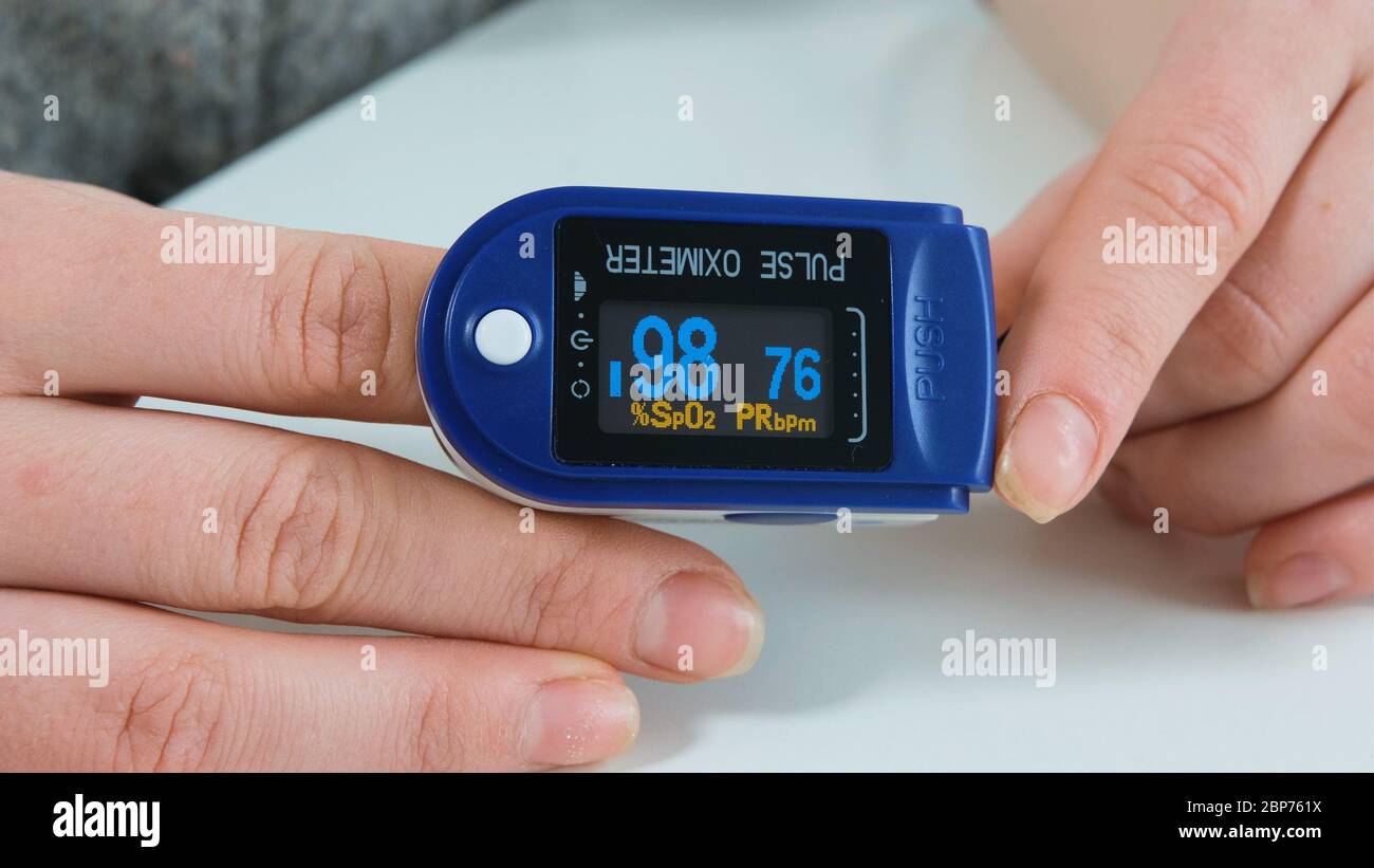 Woman holding in her hands blue Pulse Oximeter. Monitor showing ...