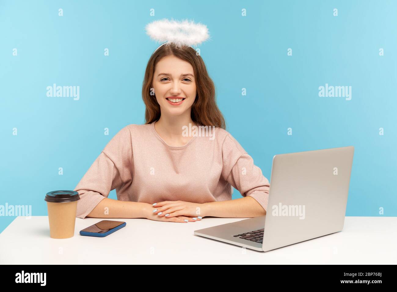Lovely angelic happy woman employee with nimbus sitting at workplace ...