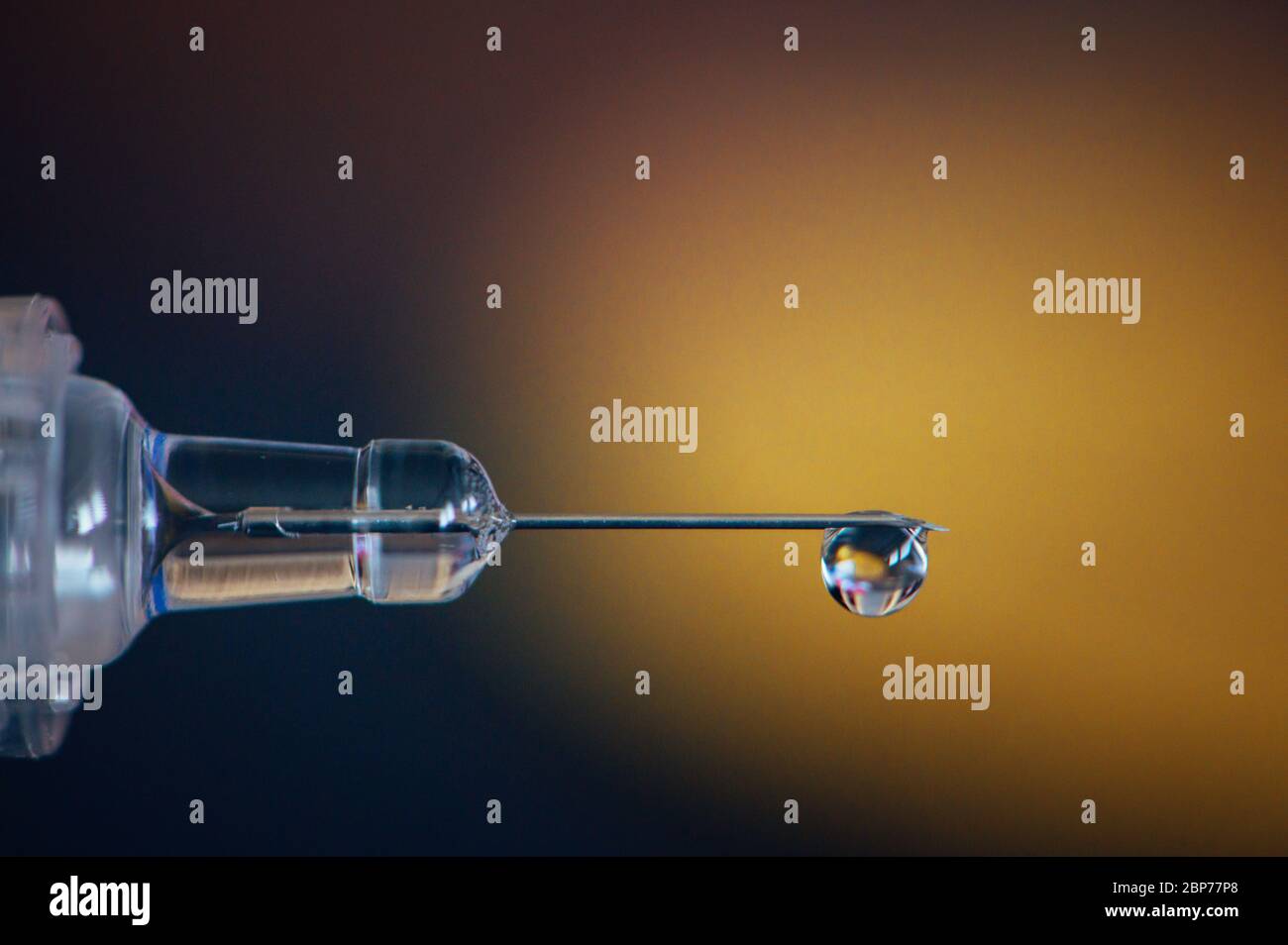 Syringe with drops, detail macro photo. Gold medal in background ...