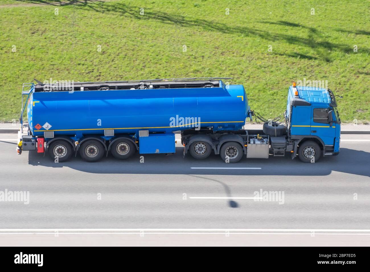 Heavy big fuel tanker with blue lame tank driving on city highway, side ...