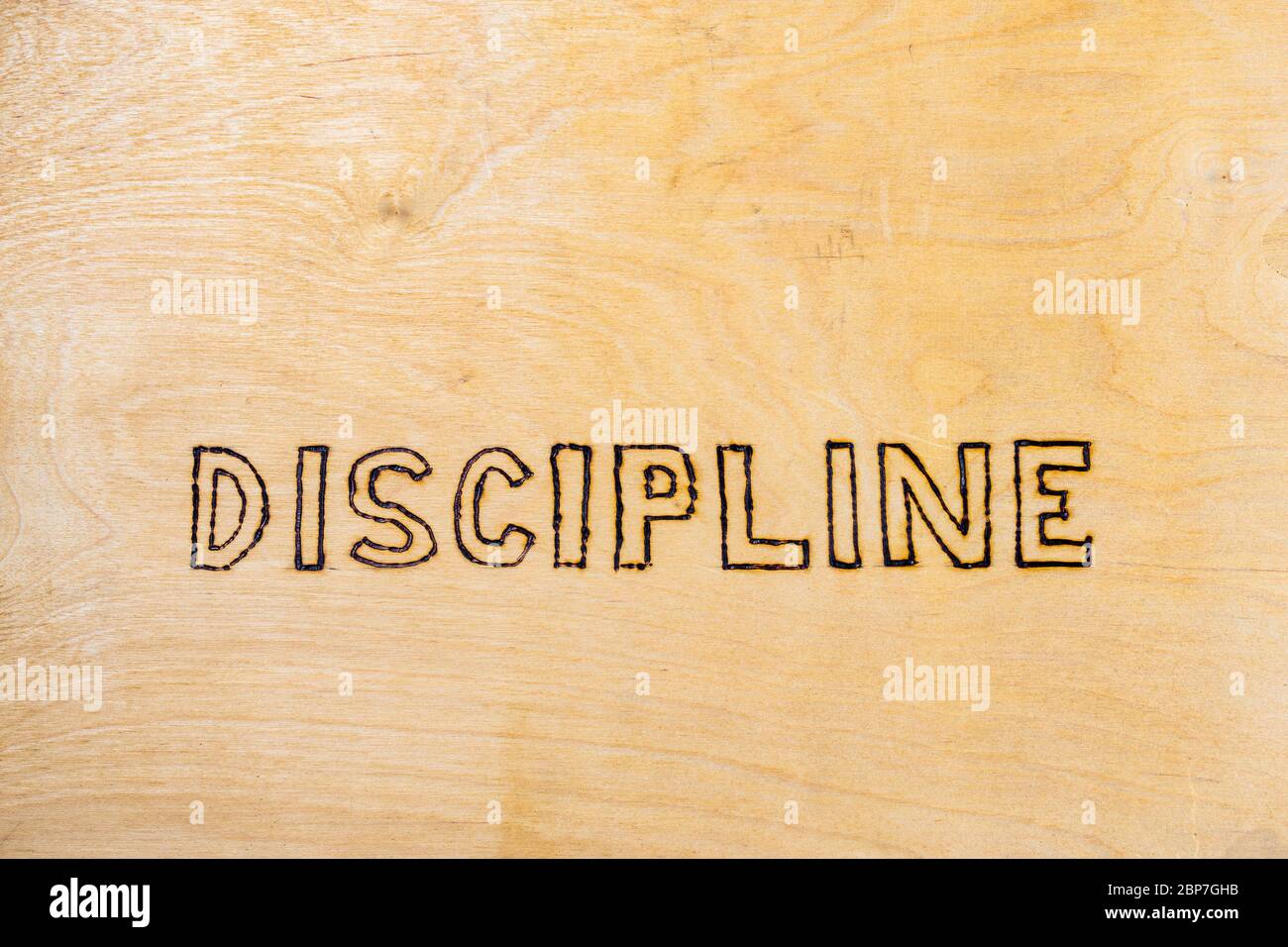 word discipline handwritten with woodburner on flat wooden surface ...