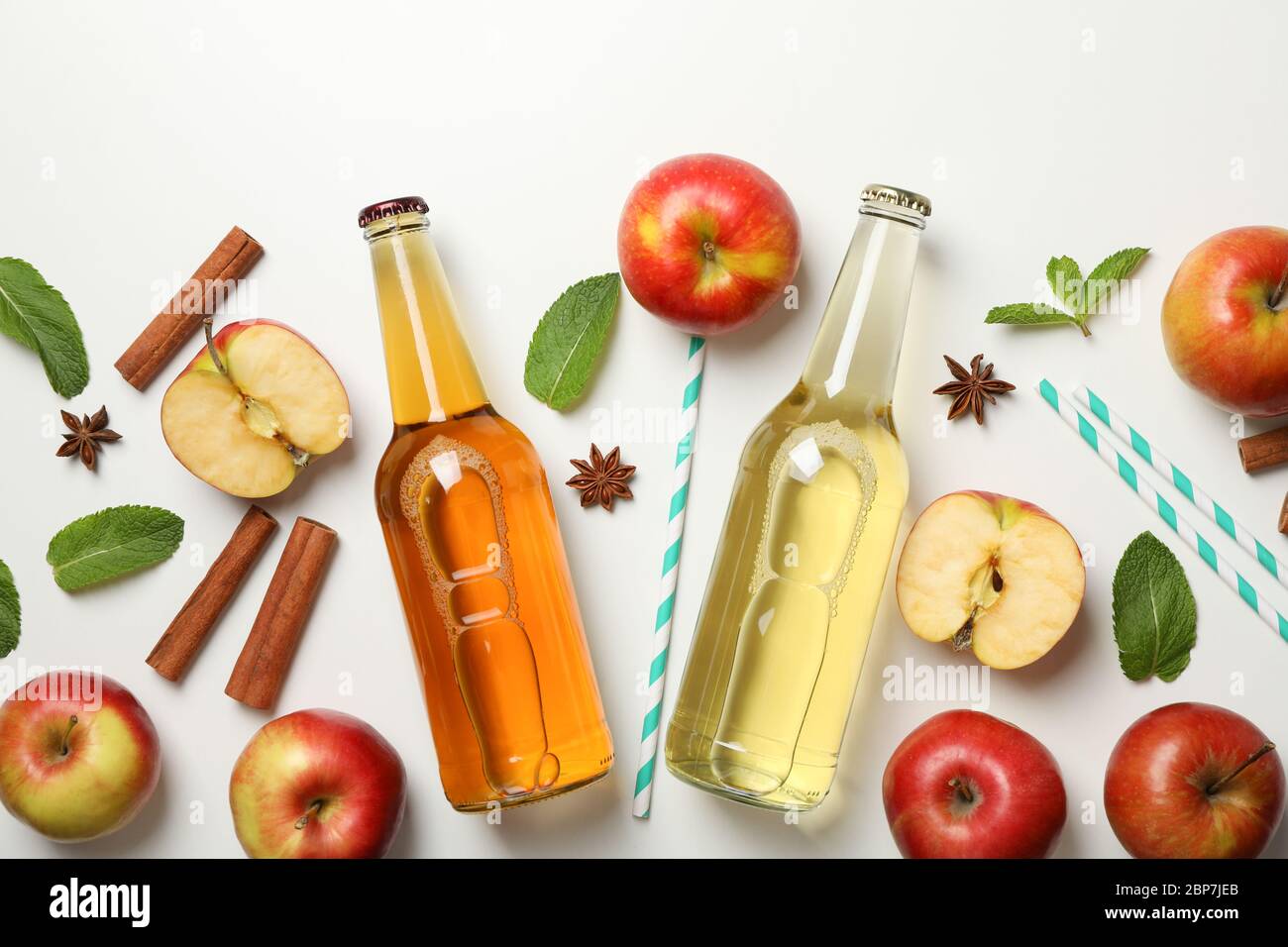 Composition with cider, apples, straws and cinnamon on white background ...