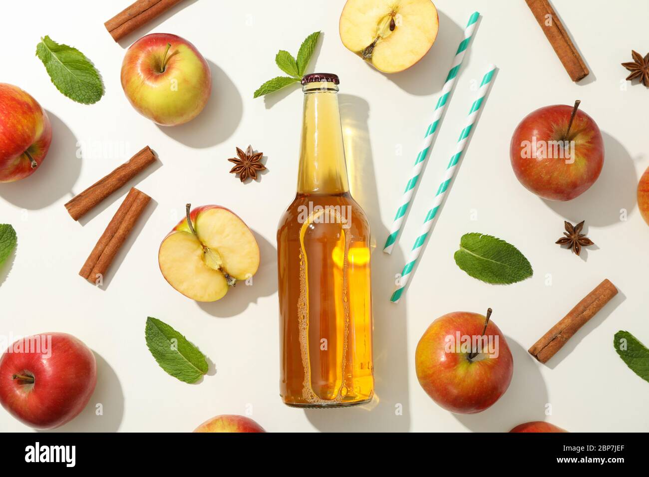 Composition with cider, apples, straws and cinnamon on white background ...