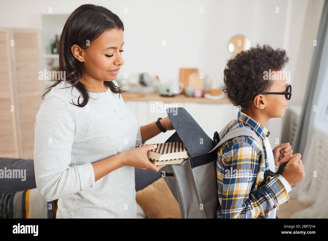 Side view portrait of smiling African-American woman putting books into ...