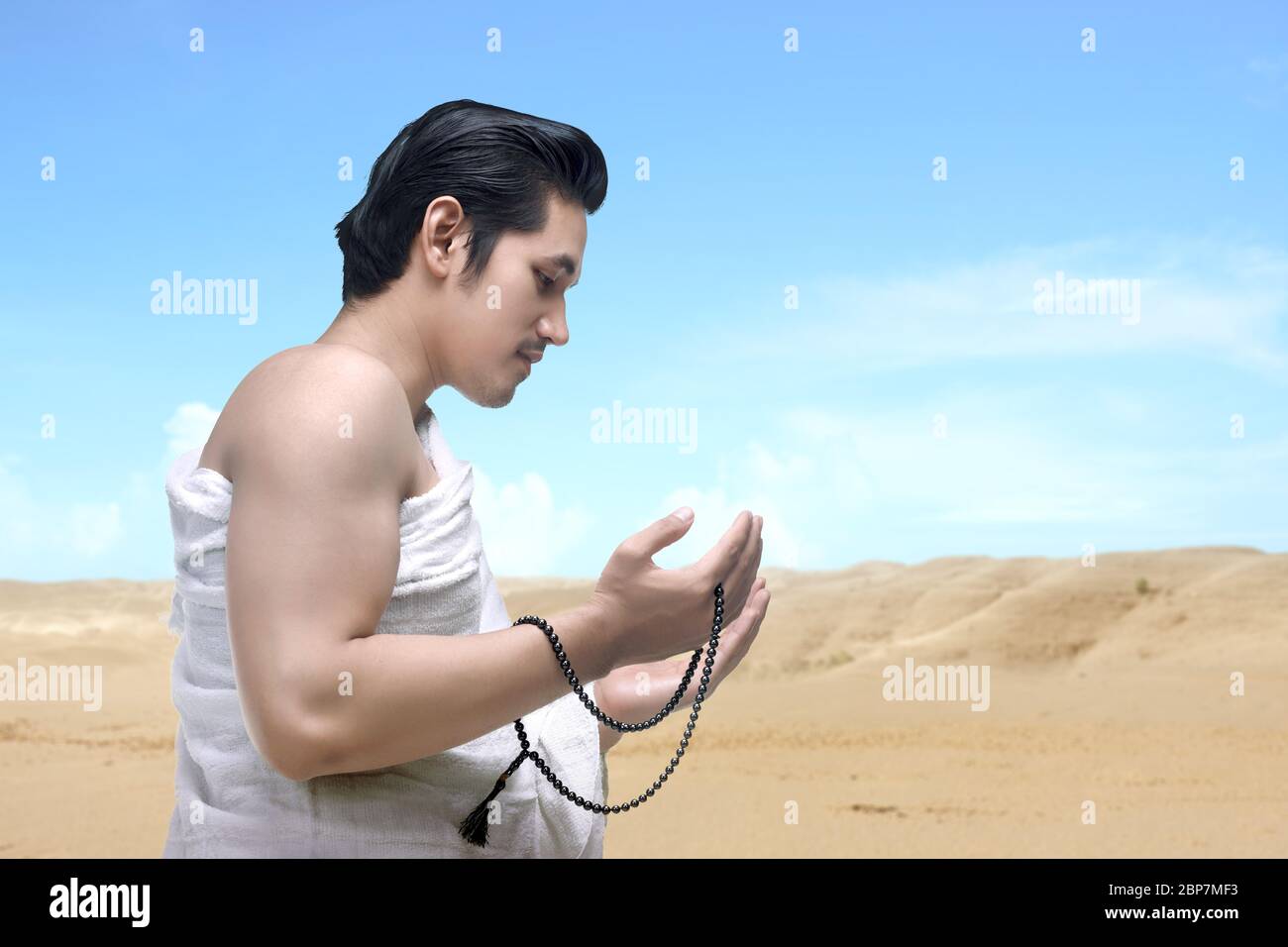 Asian Muslim man in ihram clothes praying with prayer beads on his ...