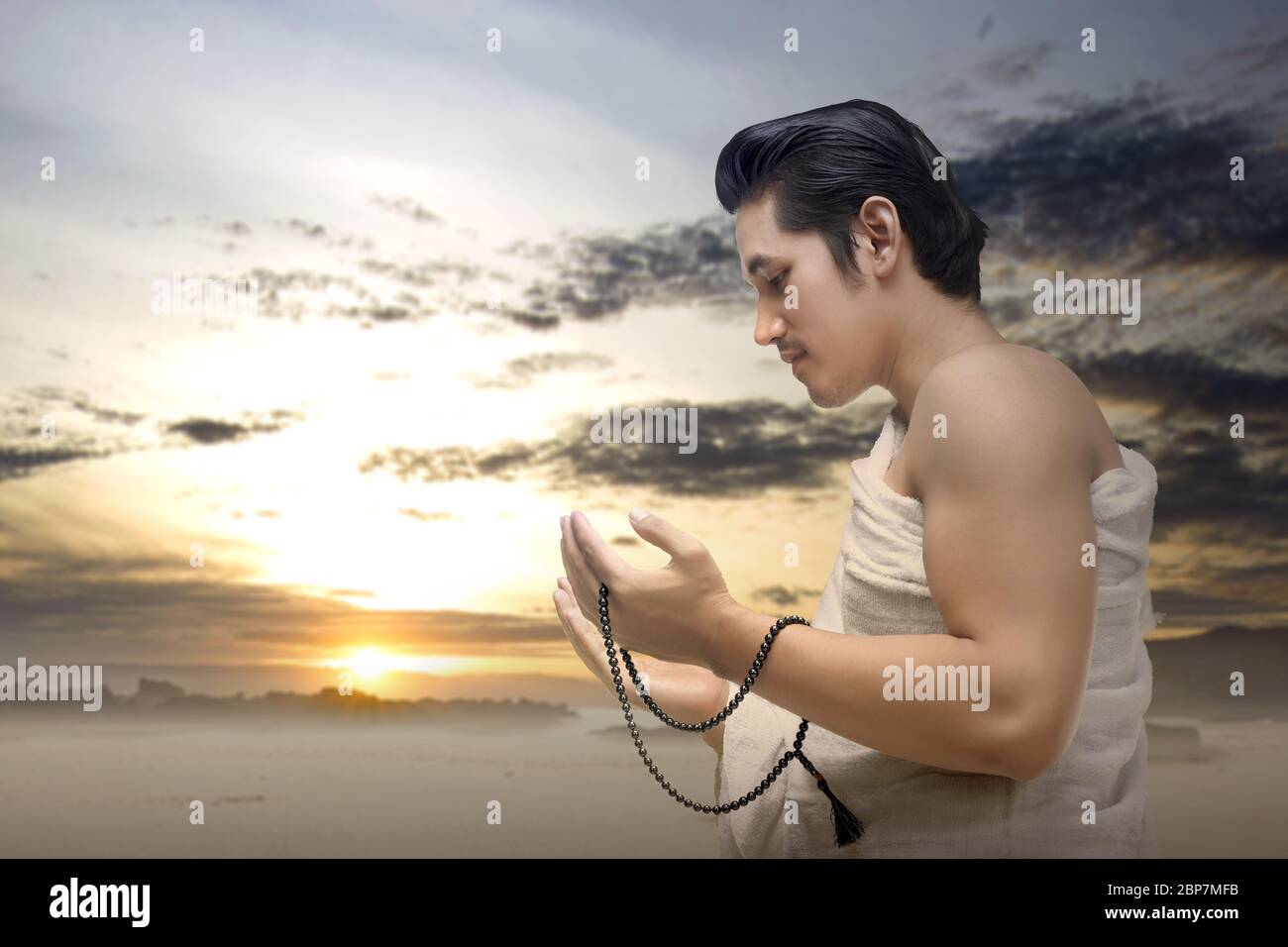 Asian Muslim man in ihram clothes praying with prayer beads on his ...