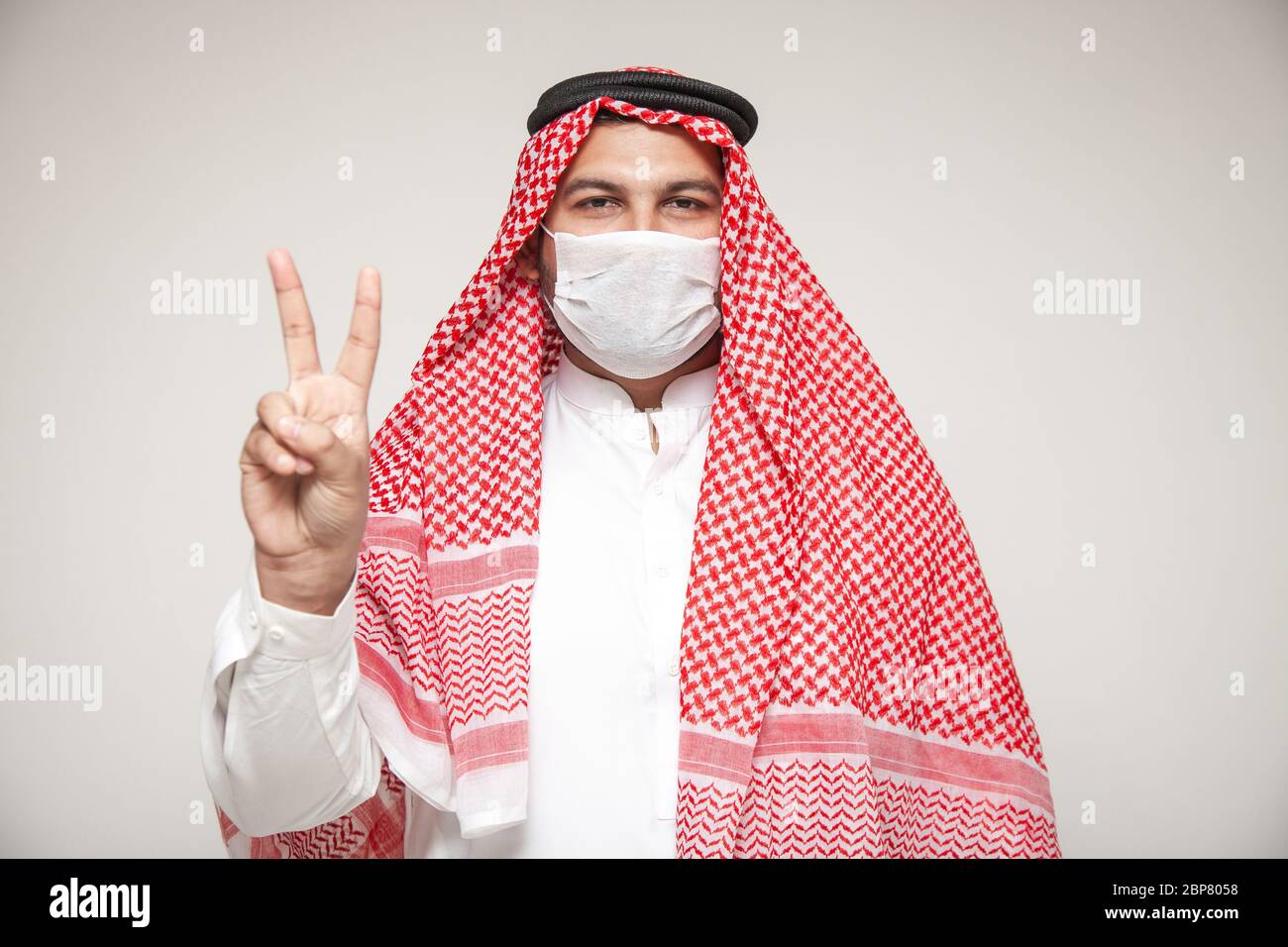 Arab man wearing corona virus covid-19 mask showing victory sign Stock ...