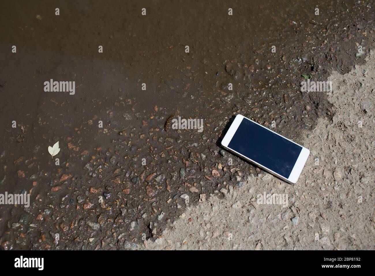 Mobile phone lying on pavement in puddle Stock Photo - Alamy