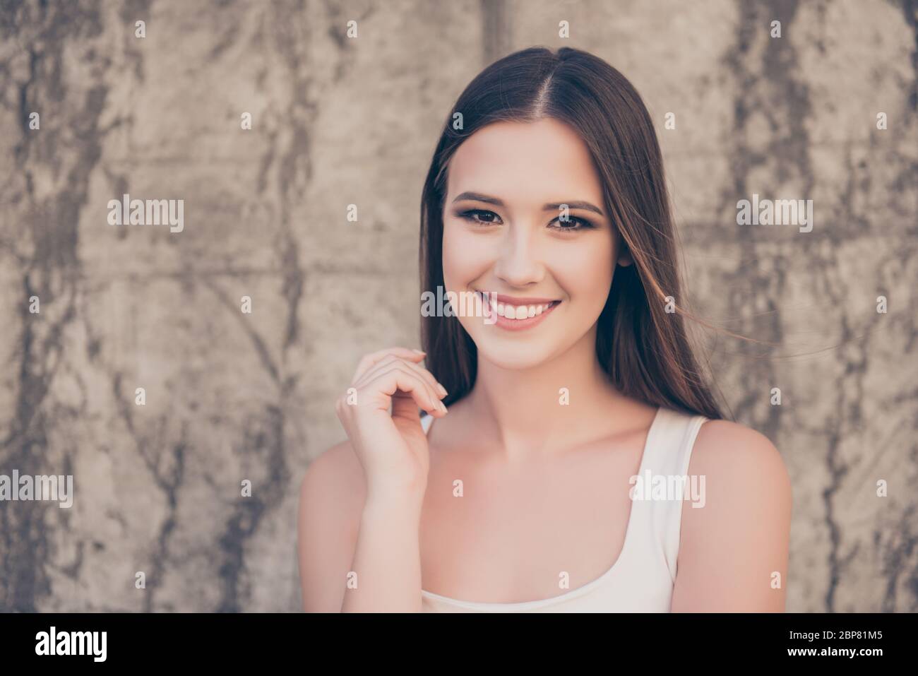 Close up of young gorgeous girl standing on the background of concrete ...