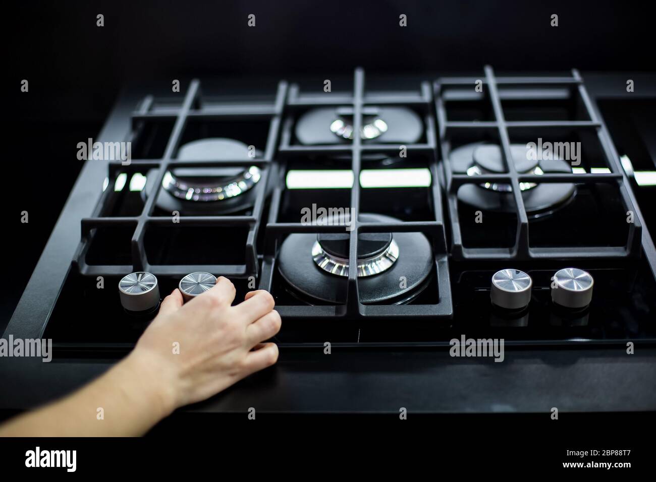 female hand turn the handle of the new modern gas stove with four ...