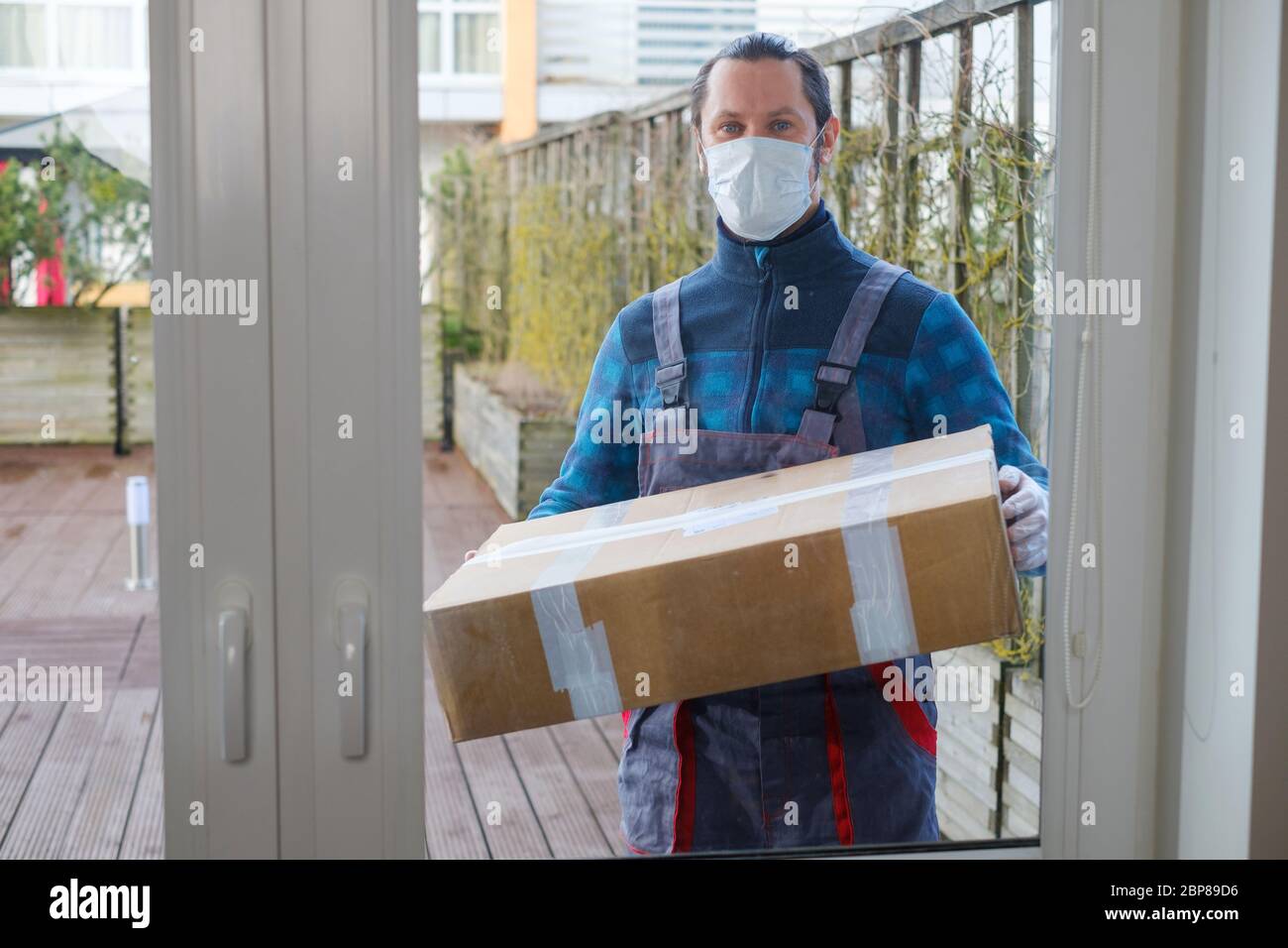 Courier protected with mask and gloves delivering parcel to a customer ...