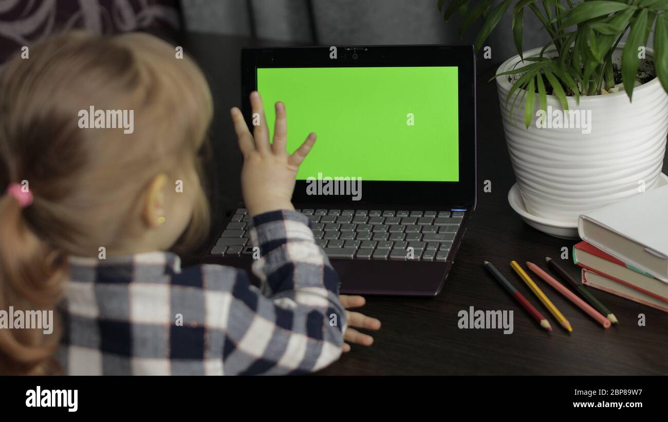 Child girl studying homework on laptop during online lesson at home. E ...