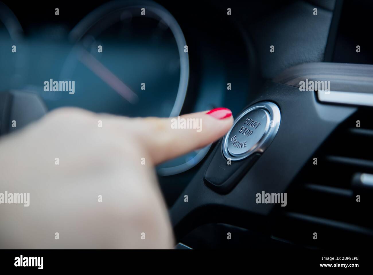 female finger presses start stop engine button on a car dashboard ...