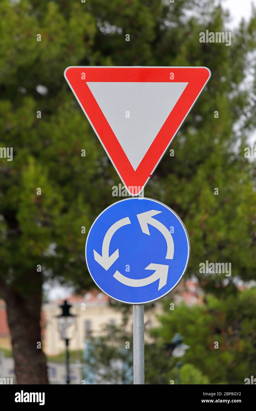 Triangle and roundabout traffic signs at circular intersection approach ...