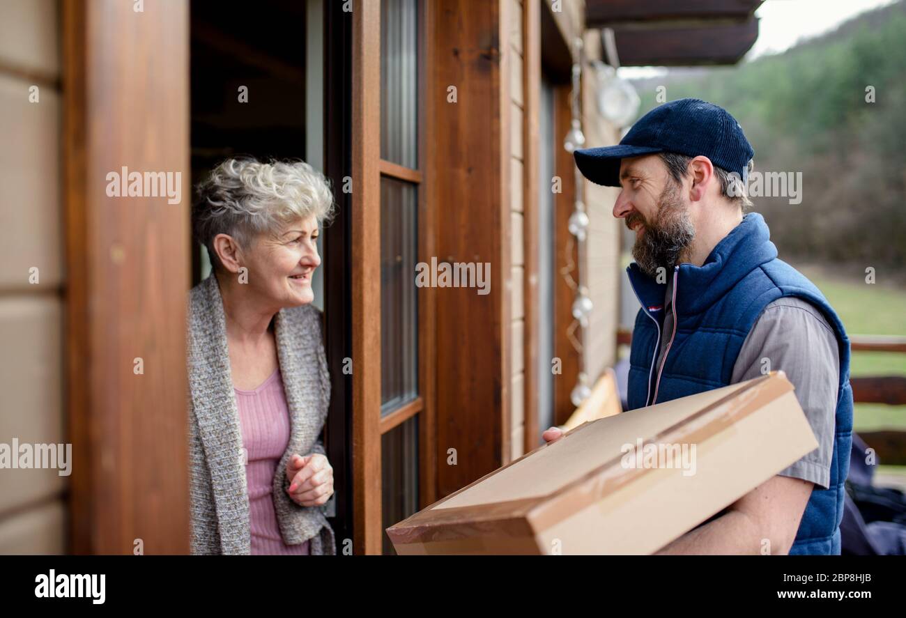 Man courier delivering parcel box to senior woman Stock Photo - Alamy