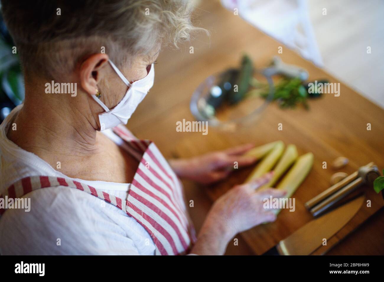 Woman with face mask cooking indoors at home, corona virus concept ...