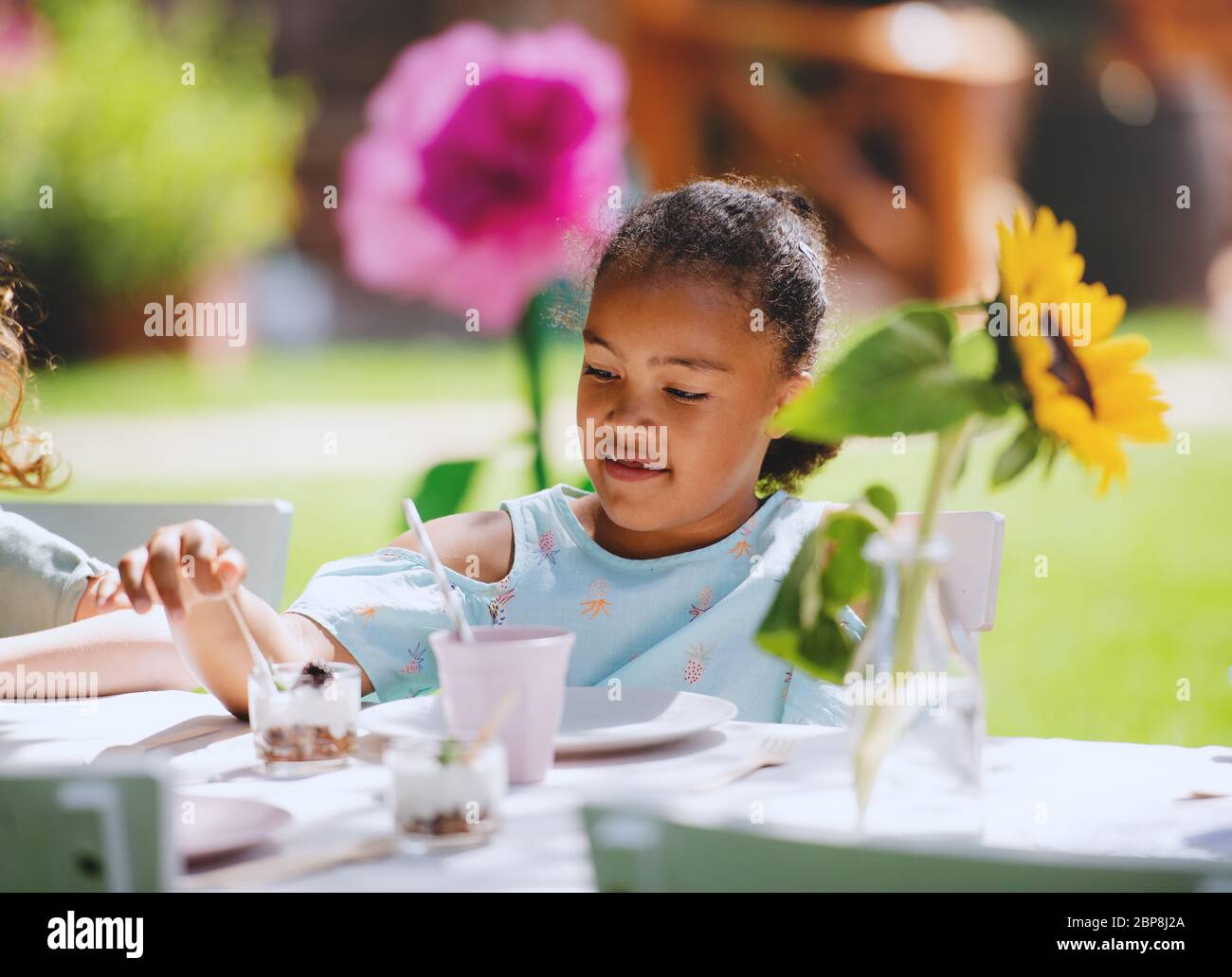 Small girl sitting outdoors in garden in summer, eating snacks Stock ...