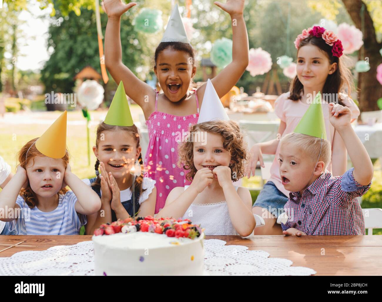 Down syndrome child with friends on birthday party outdoors in garden ...