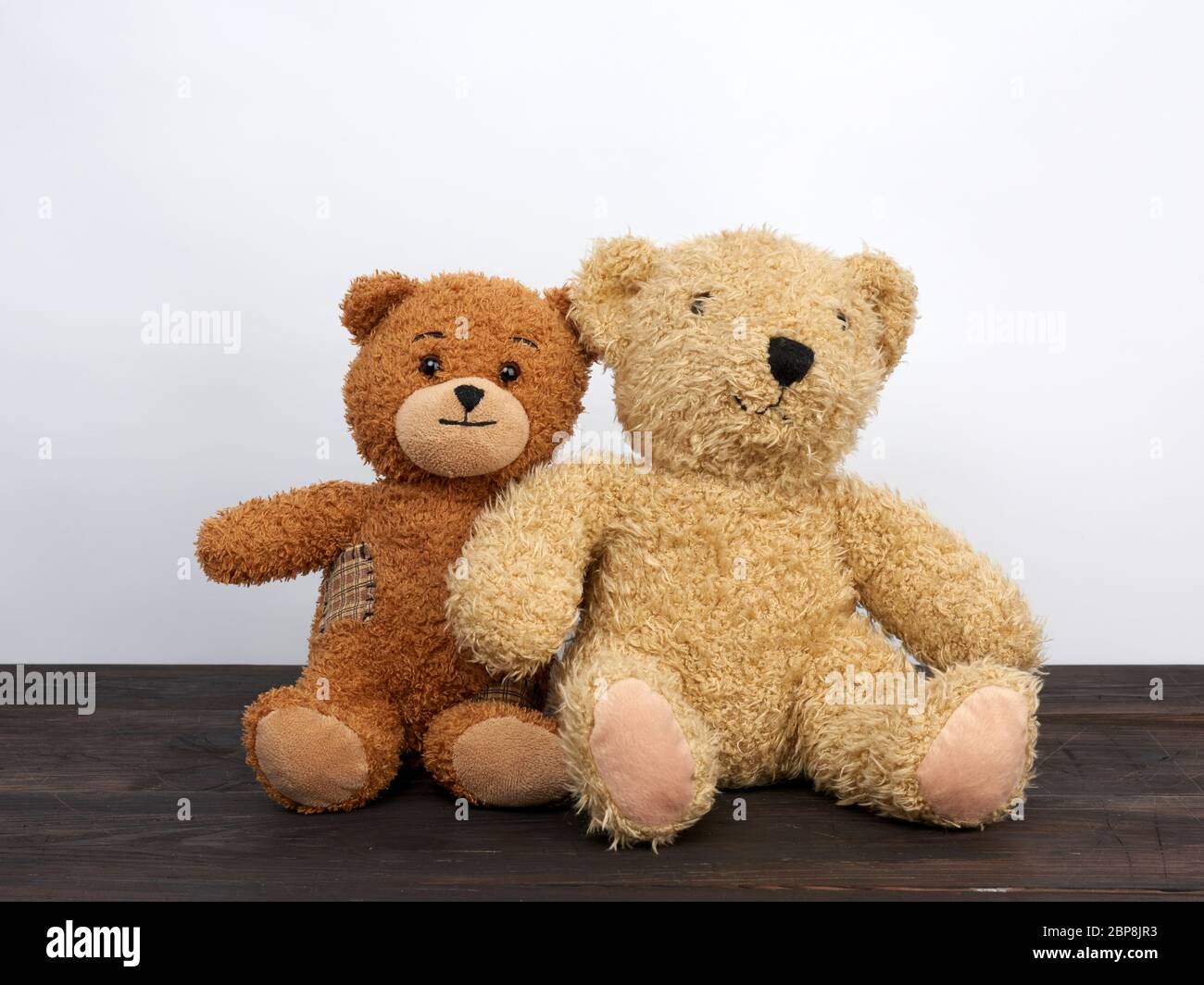brown teddy bears are sitting on a brown wooden table, white background ...