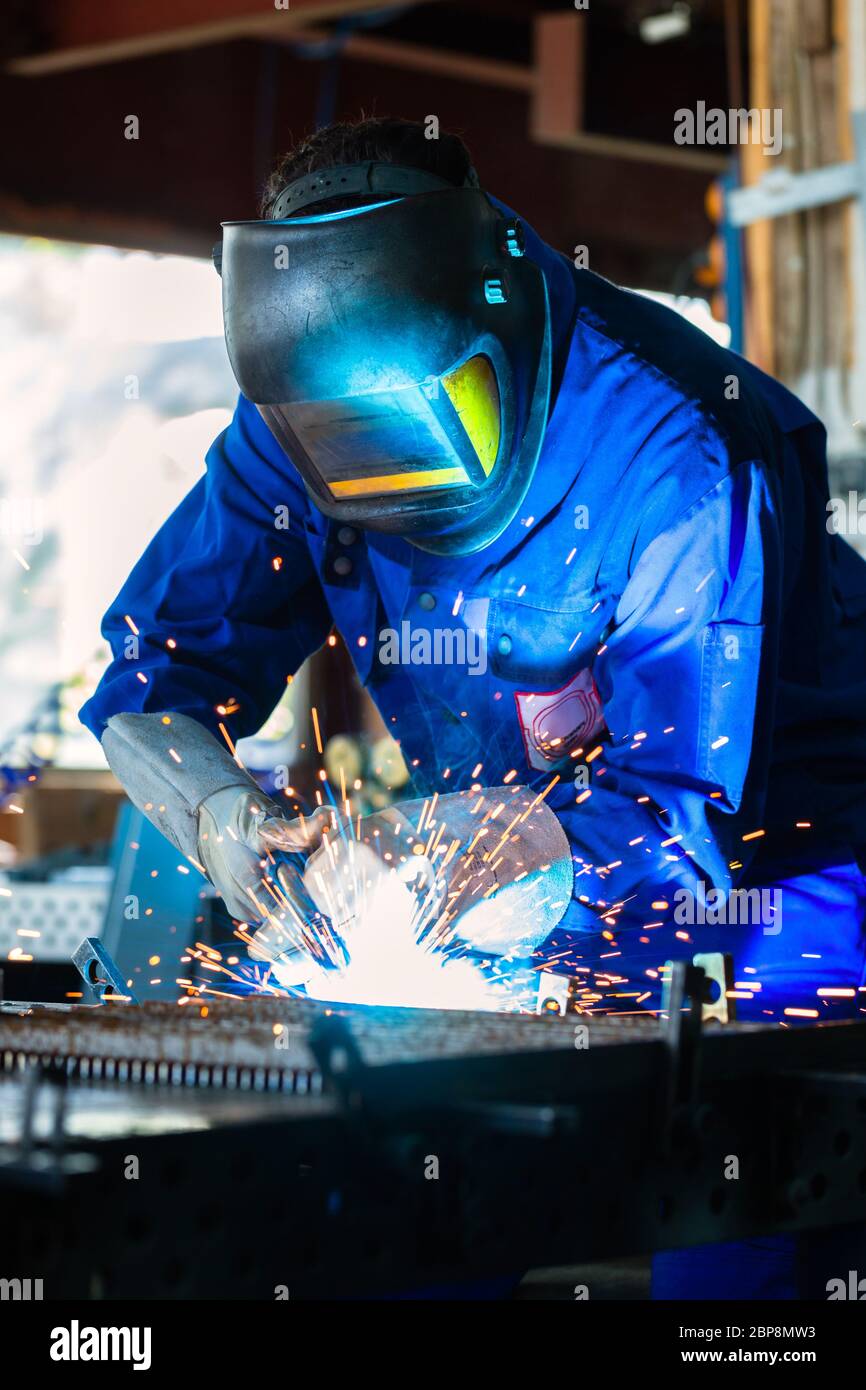 Welder bonding metal with welding device in workshop, lots of sparks to ...