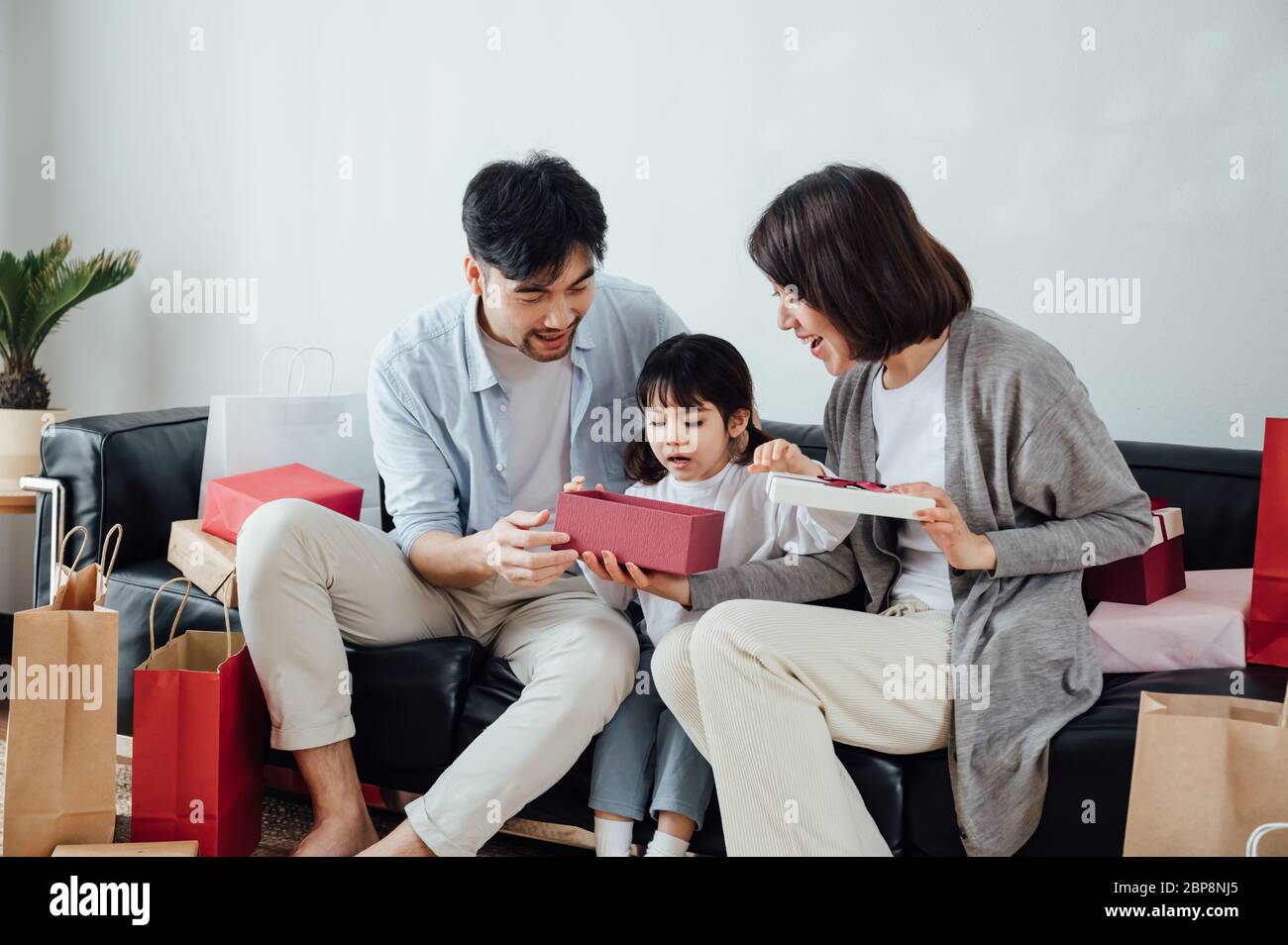Mom and Dad and daughter at home opening presents Stock Photo - Alamy