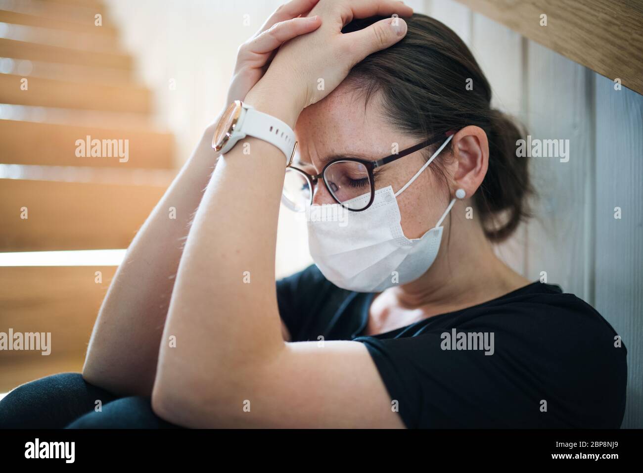 Sad woman with face mask sitting indoors at home, Corona virus and ...