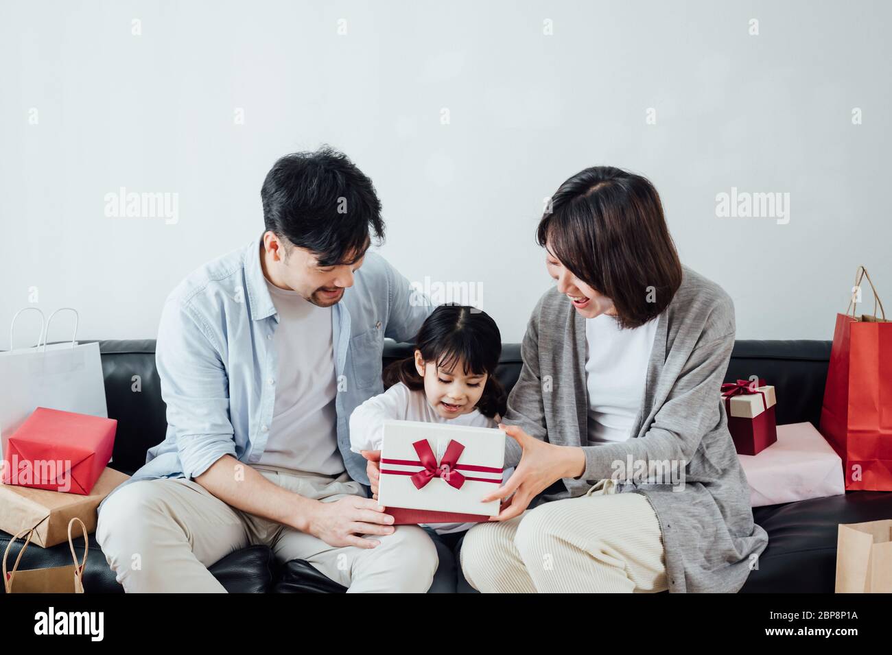 Mom and Dad and daughter at home opening presents Stock Photo - Alamy