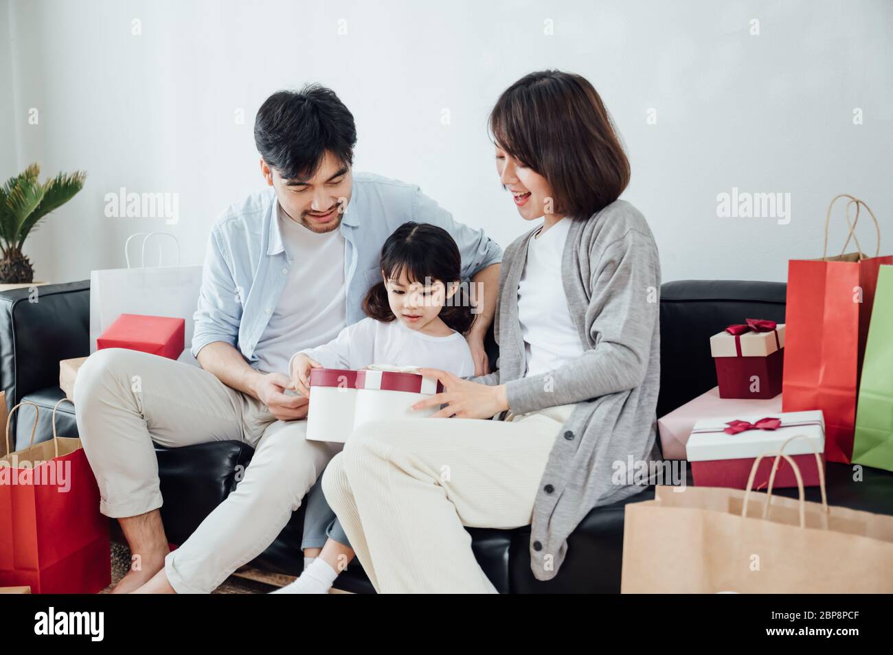 Mom and Dad and daughter at home opening presents Stock Photo - Alamy