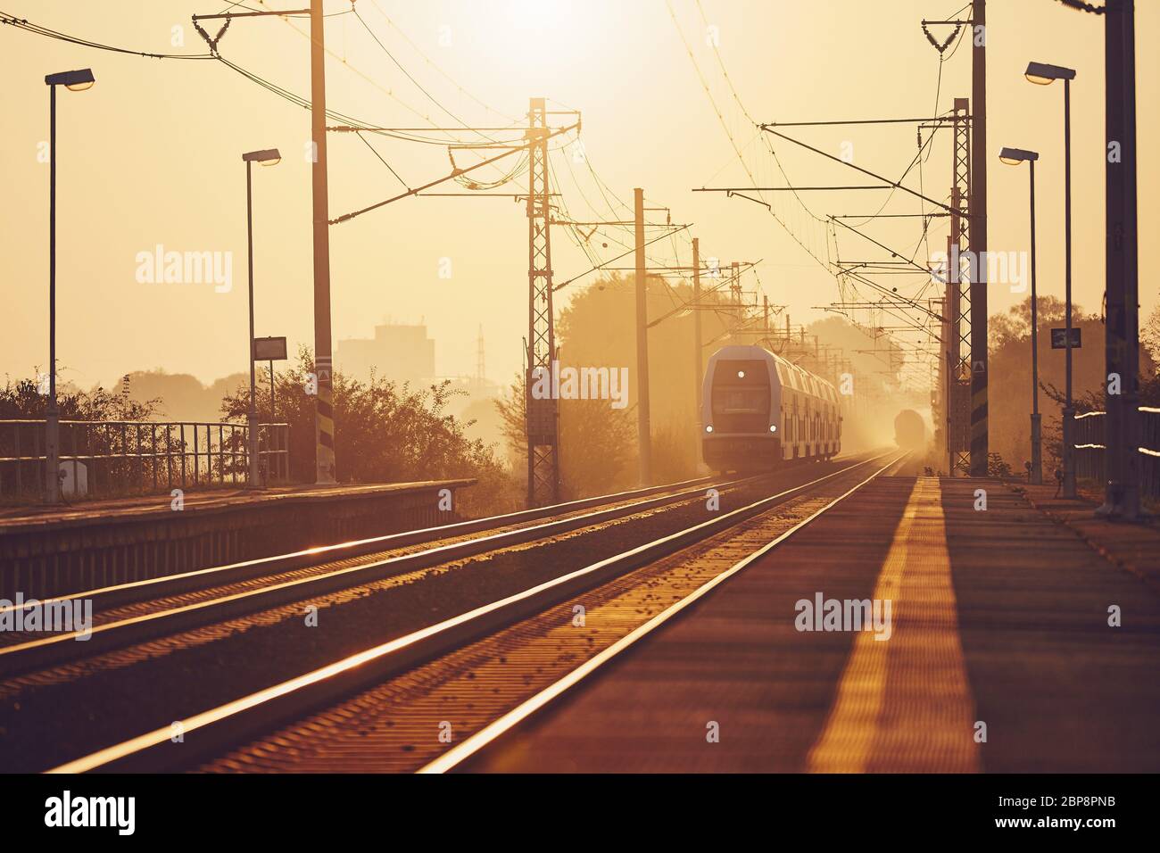 Passenger train commuting to railroad station at golden sunrise Stock ...