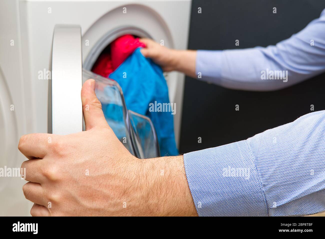 man takes out the laundry from the washing machine. men puts clothes in ...