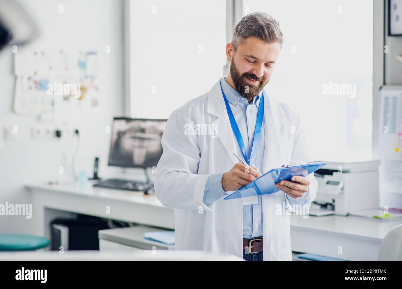 Dentist with clipboard in modern dental surgery, writing Stock Photo ...
