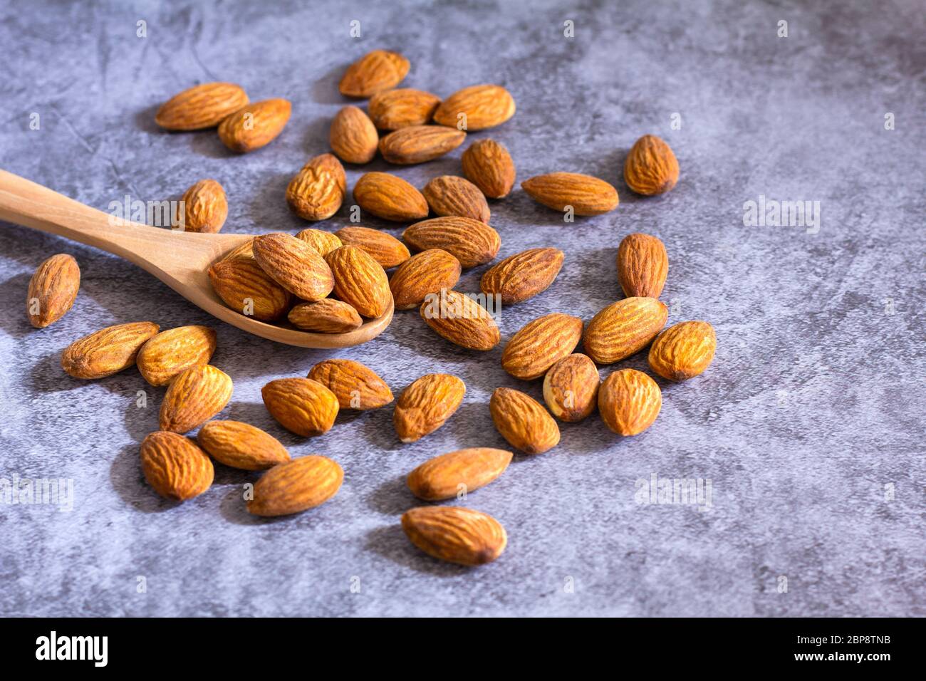 Almonds with wooden spoon on the dark table Stock Photo - Alamy