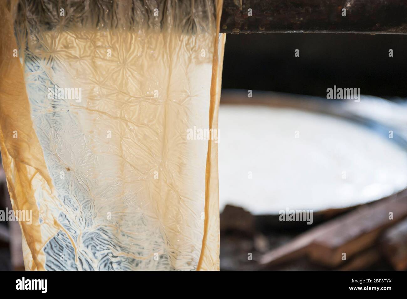 Close up of a tofu skin drying with a pan of boiling soy milk in the ...