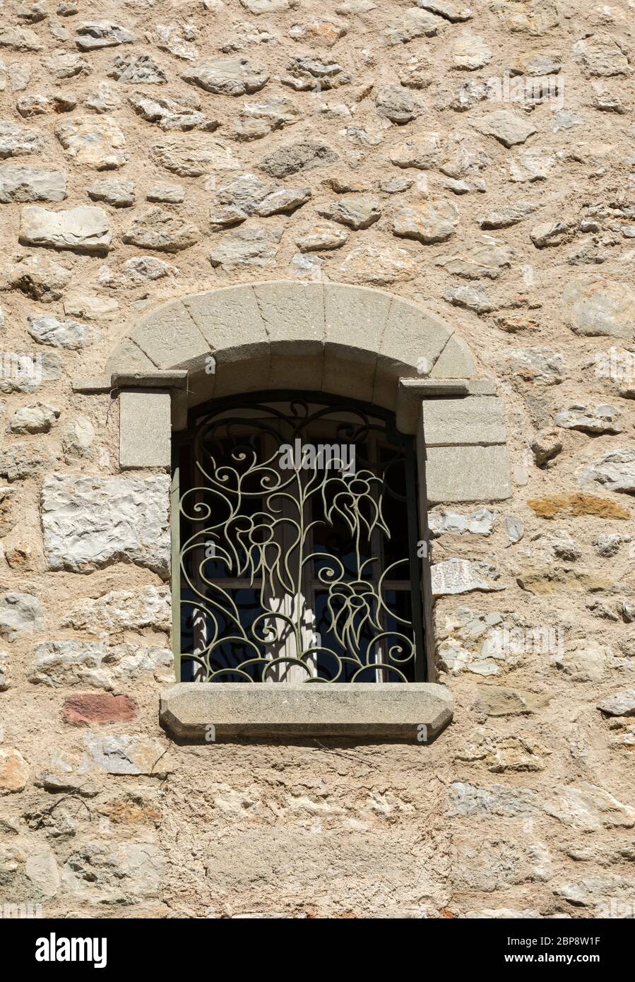 Iron, decorative lattice in the window of a stone house. Provence ...