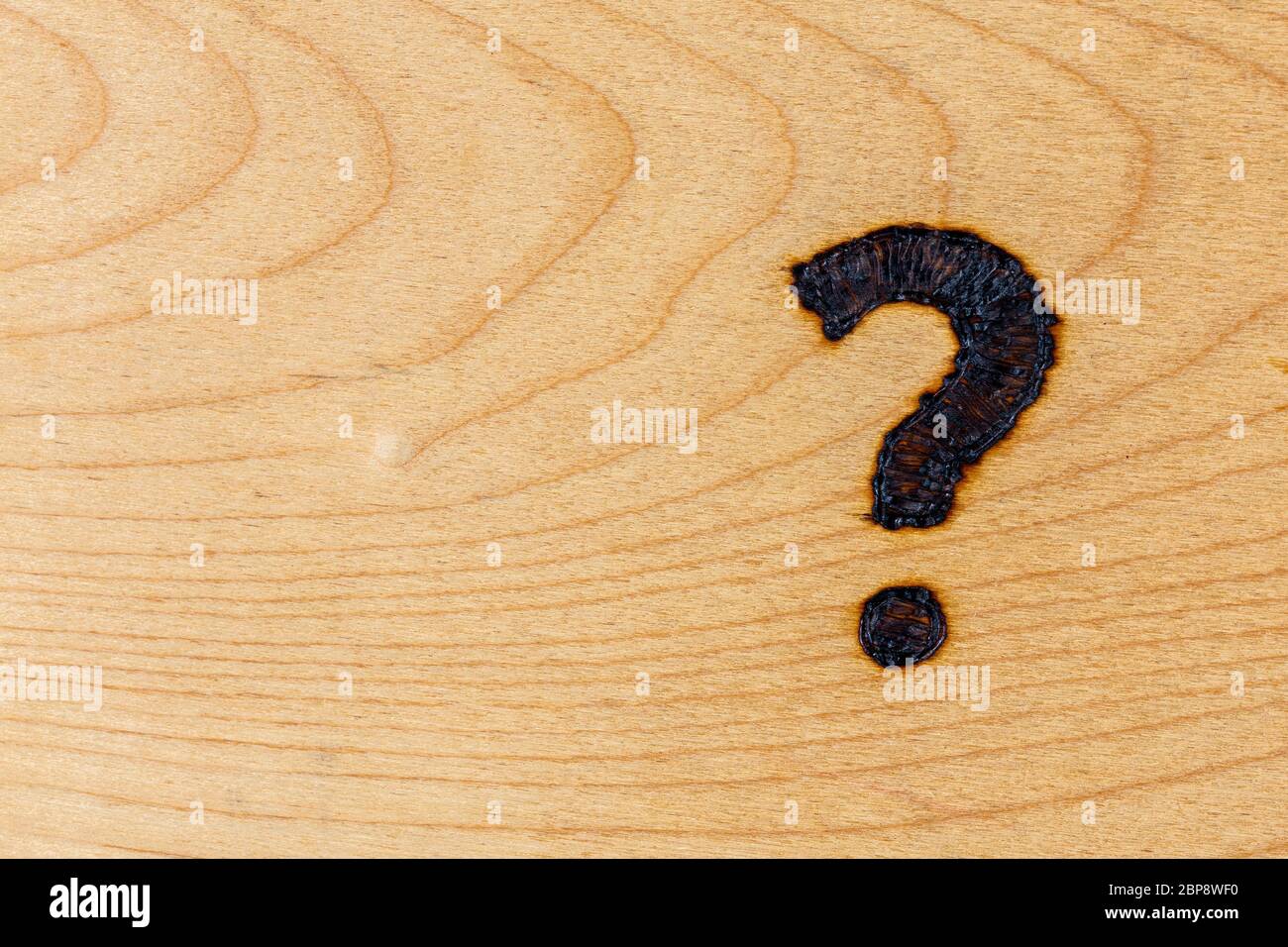 question mark drawn with handheld woodburner on bright flat wooden ...