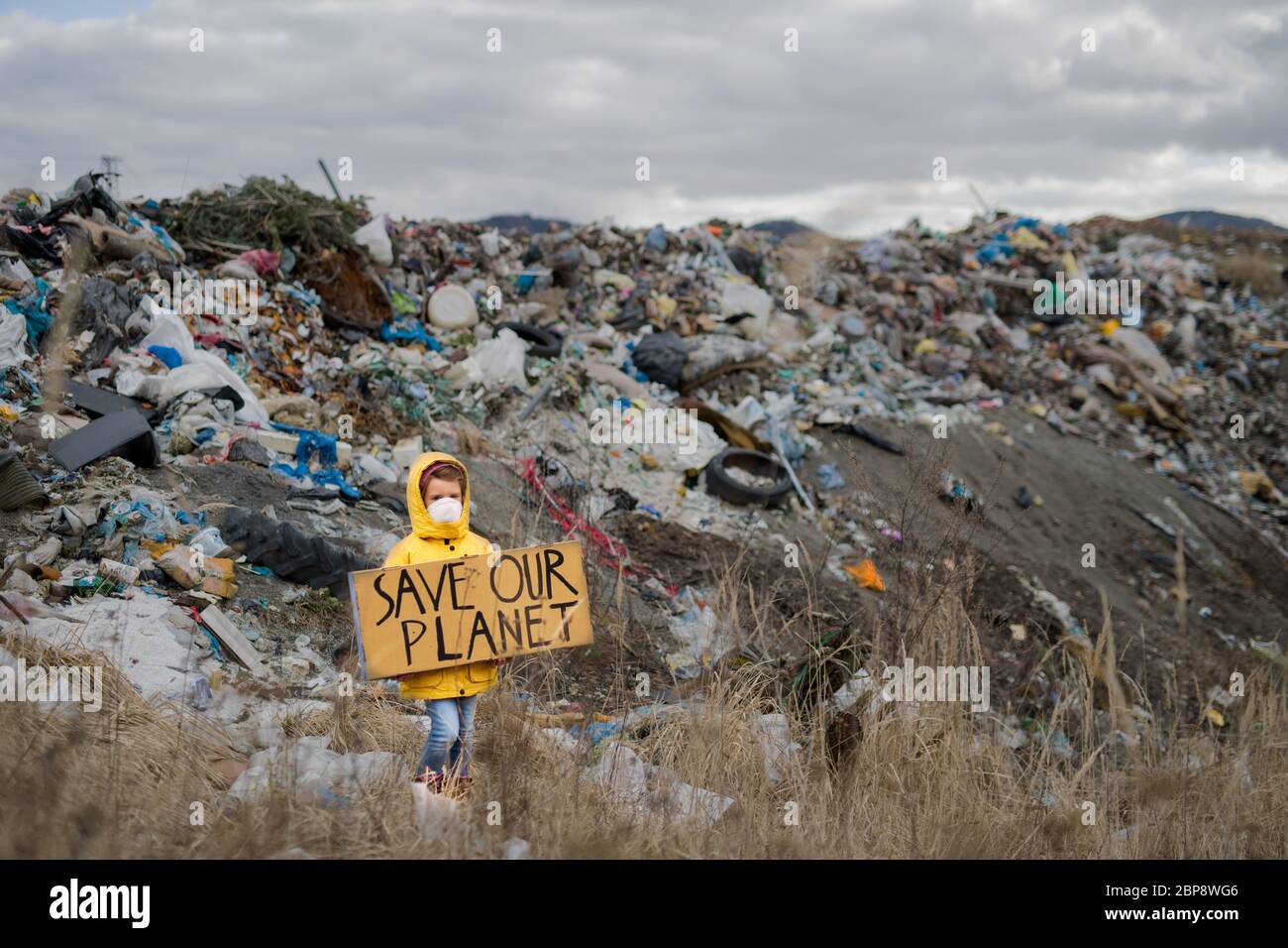 Small child holding placard poster on landfill, environmental pollution ...