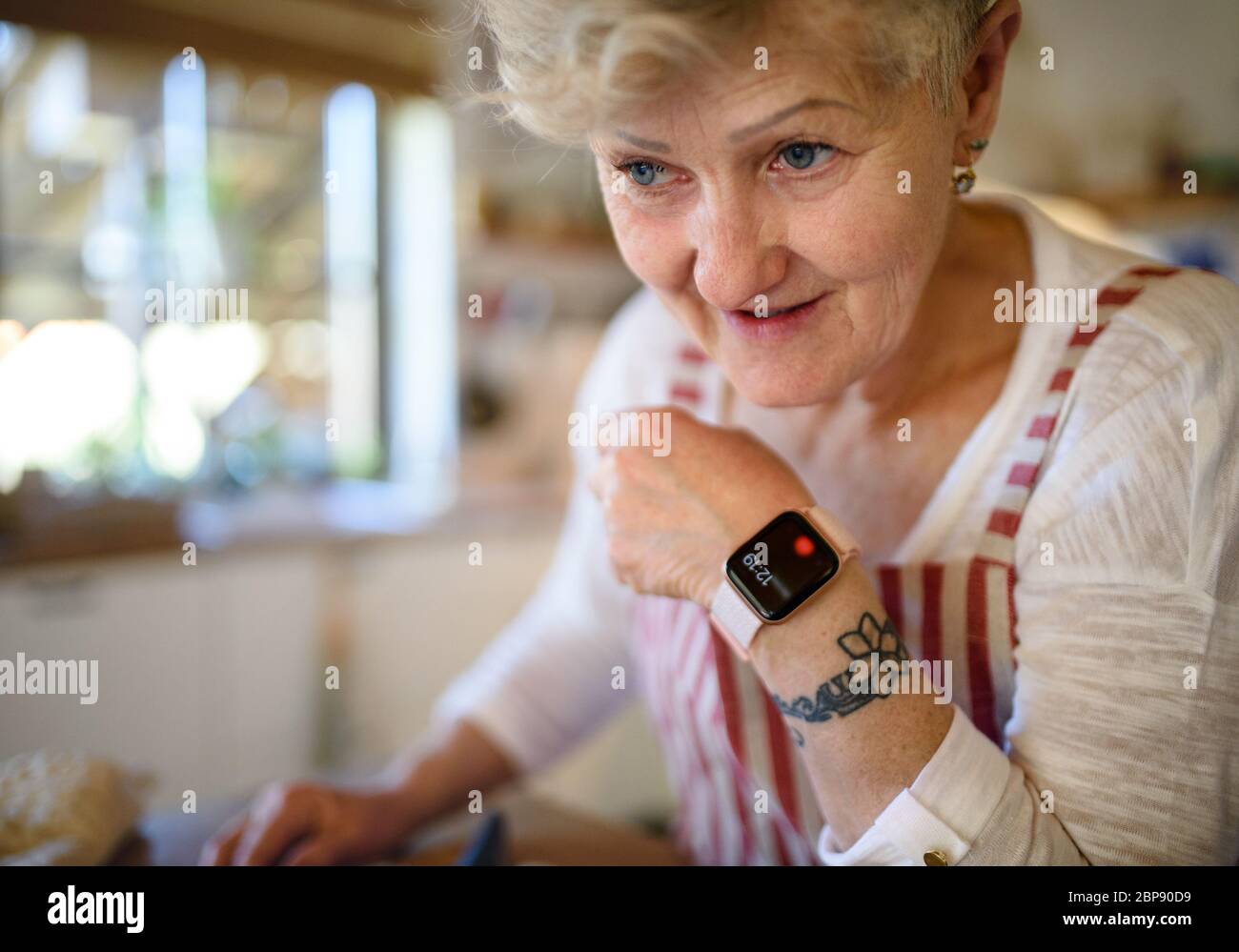 Senior woman with apron and smartwatch indoors at home Stock Photo - Alamy
