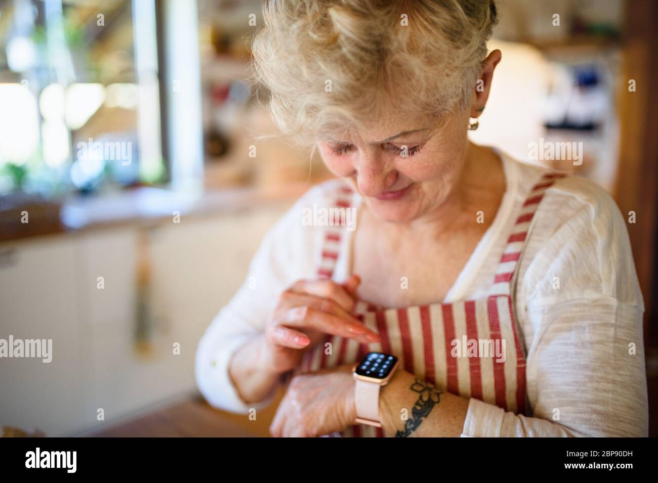 Senior woman with apron indoors at home, using smartwatch Stock Photo ...