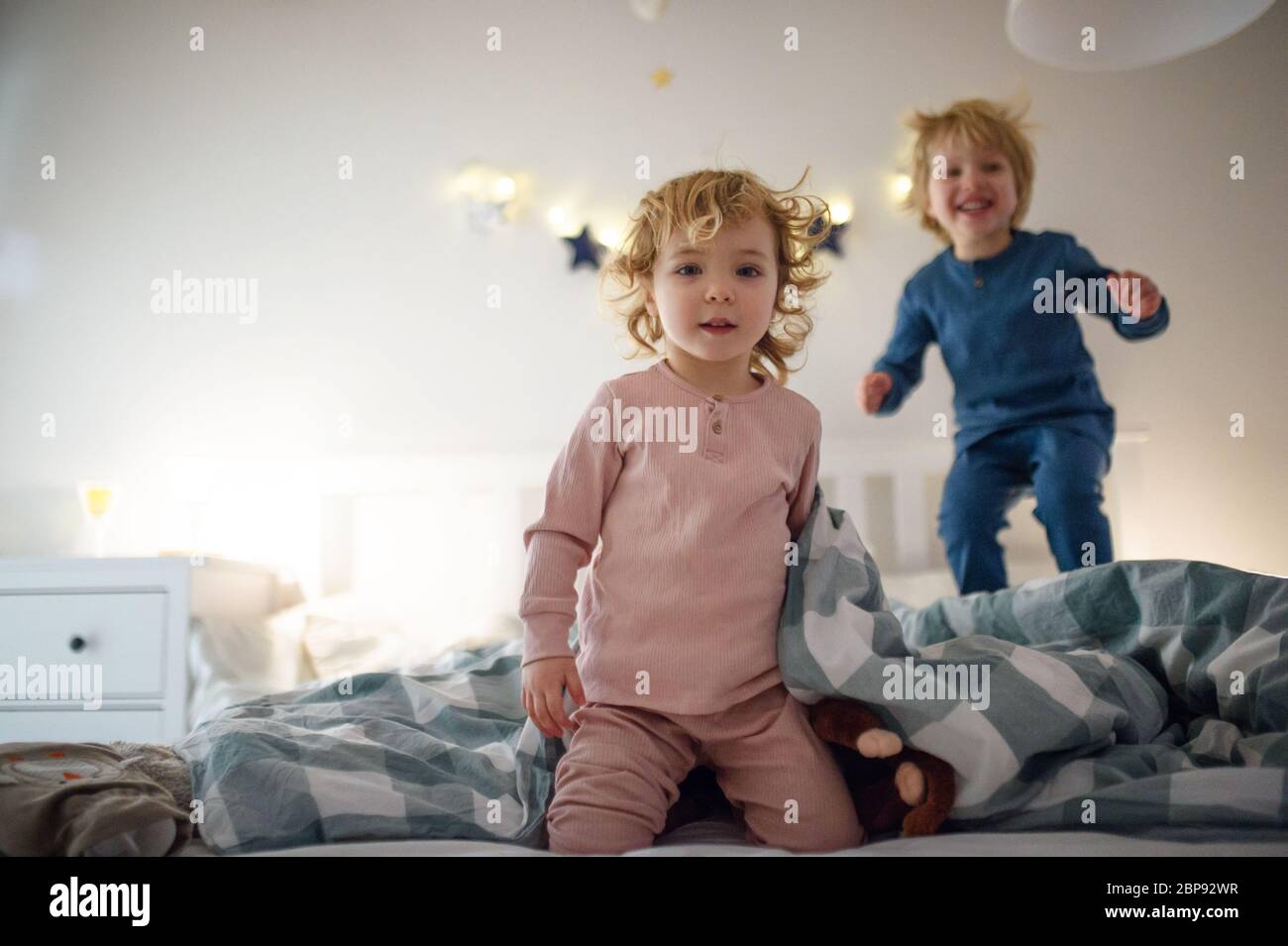 Two small children jumping on bed indoors at home, having fun Stock ...