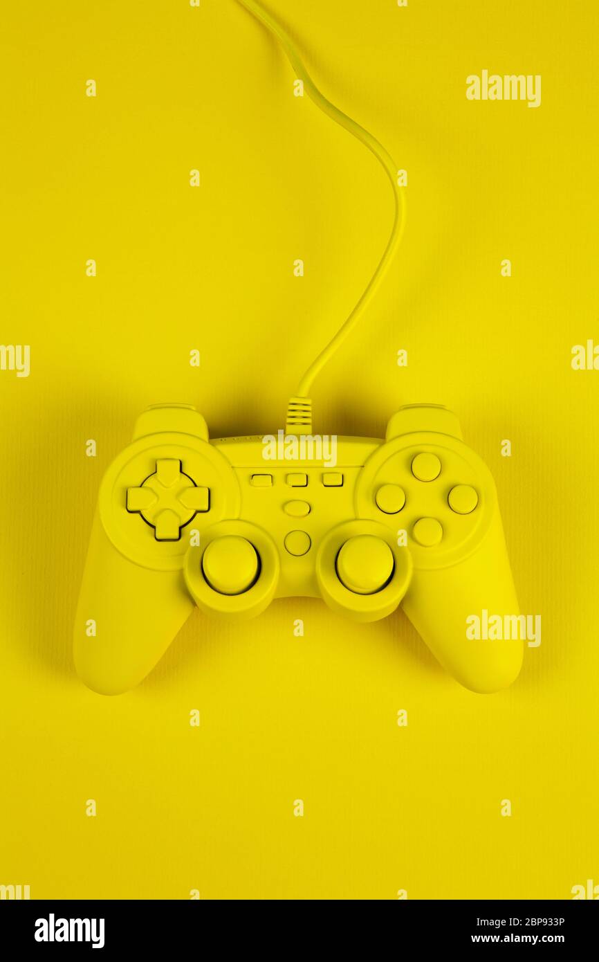 a yellow painted video game controller on a plain background of the ...