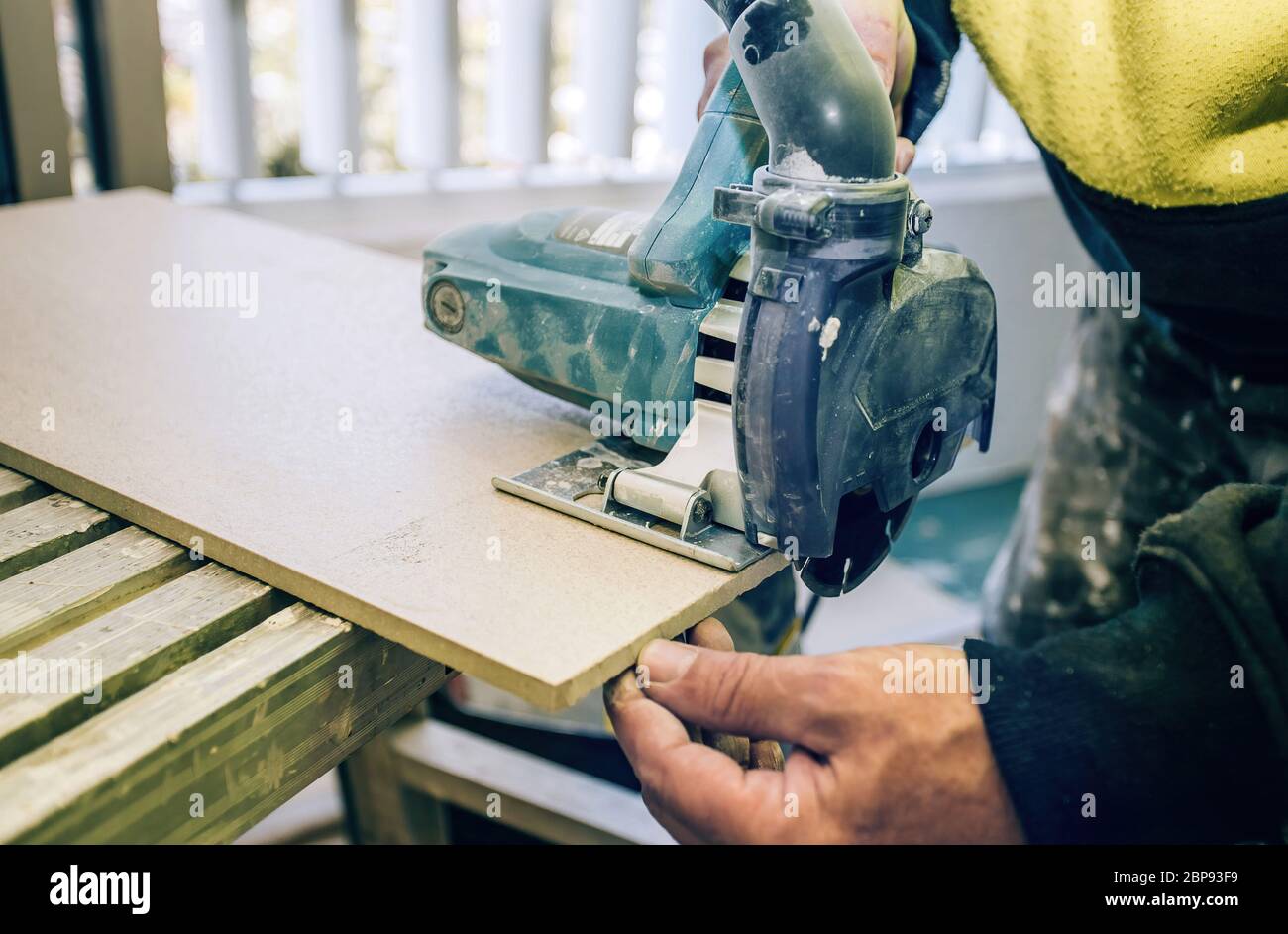 Master cuts the tile using an angle grinder with special diamond disc ...