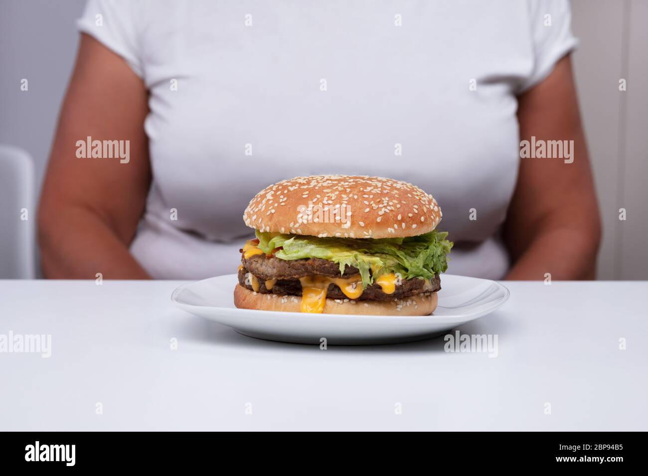 Fast Food Hamburger On White Dish Over The Table In Front Of Overweight ...