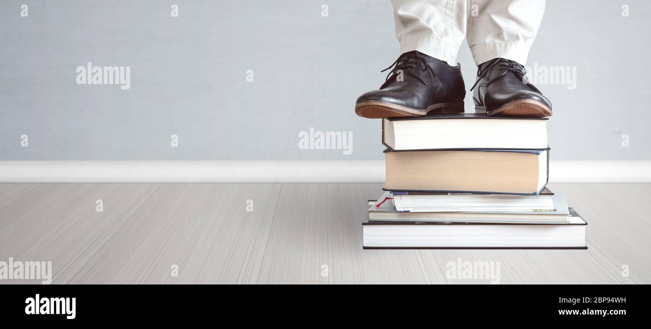 Education concept - feet standing on a stack of books Stock Photo - Alamy